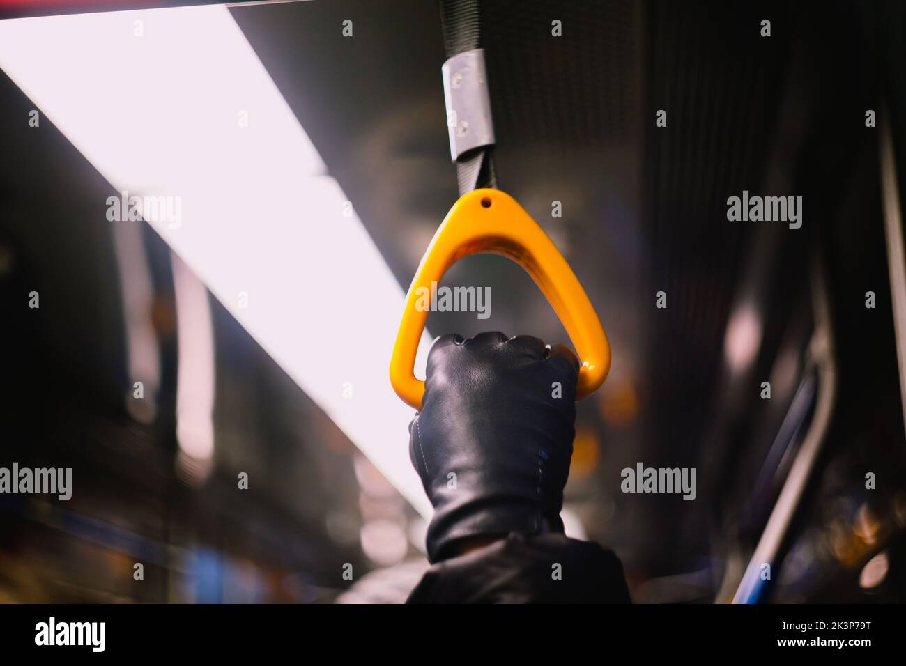 A shallow focus shot of human hand in black leather glow holding onto ...