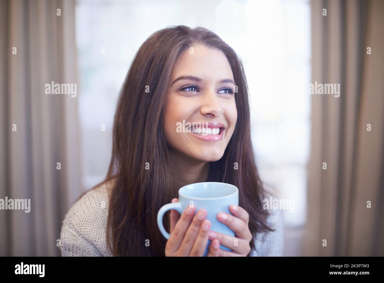 Starting the day off right. a young woman enjoying a cup of coffee at ...