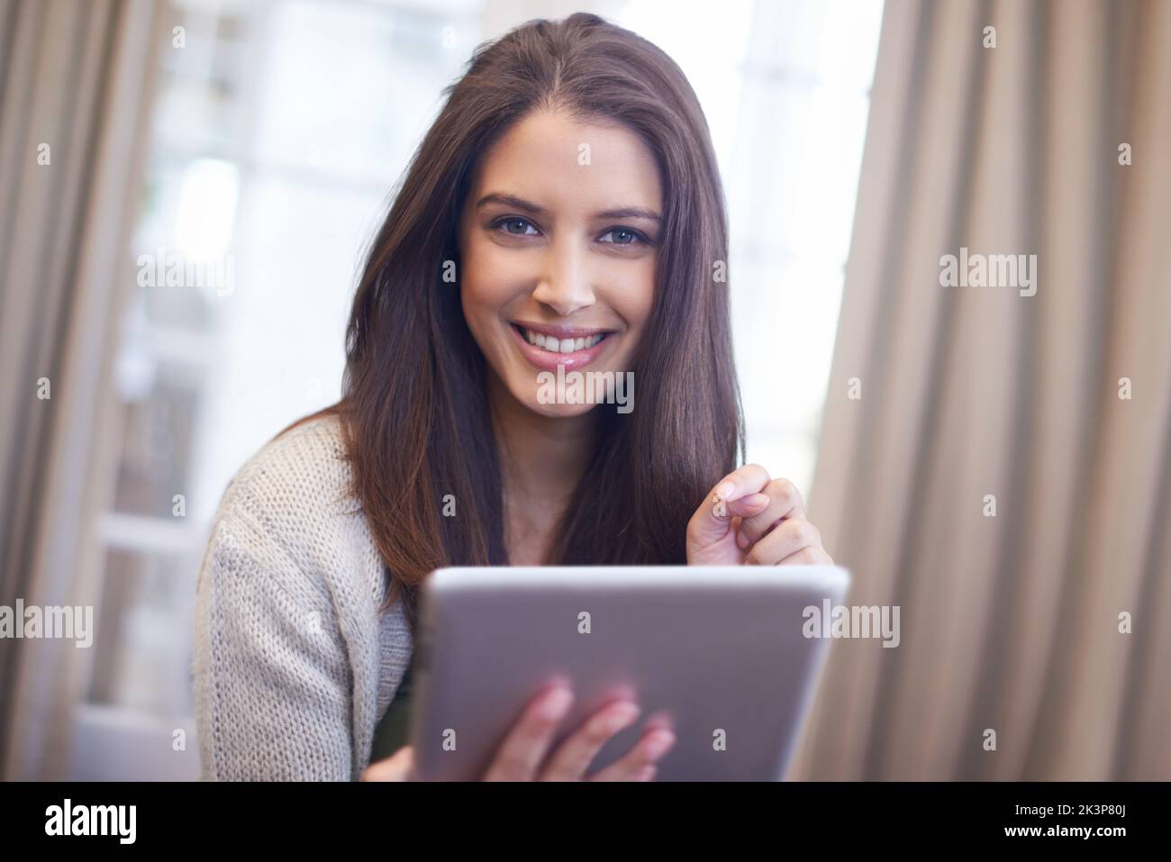 Updating her blog. A young woman working on her digital tablet Stock ...
