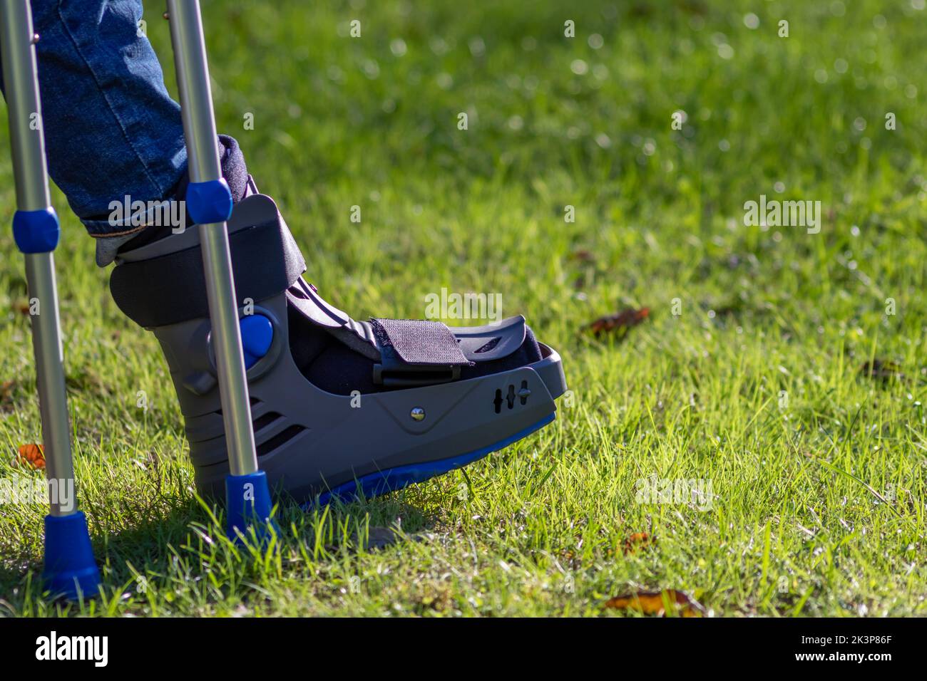 Boy with broken foot and orthopedic shoe or walker after bone fracture ...