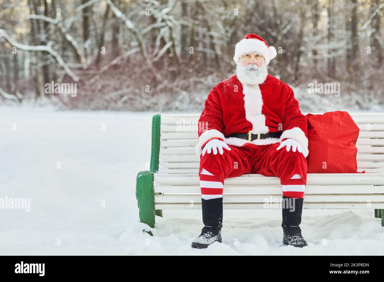 Full length portrait of traditional santa Claus sitting on bench ...