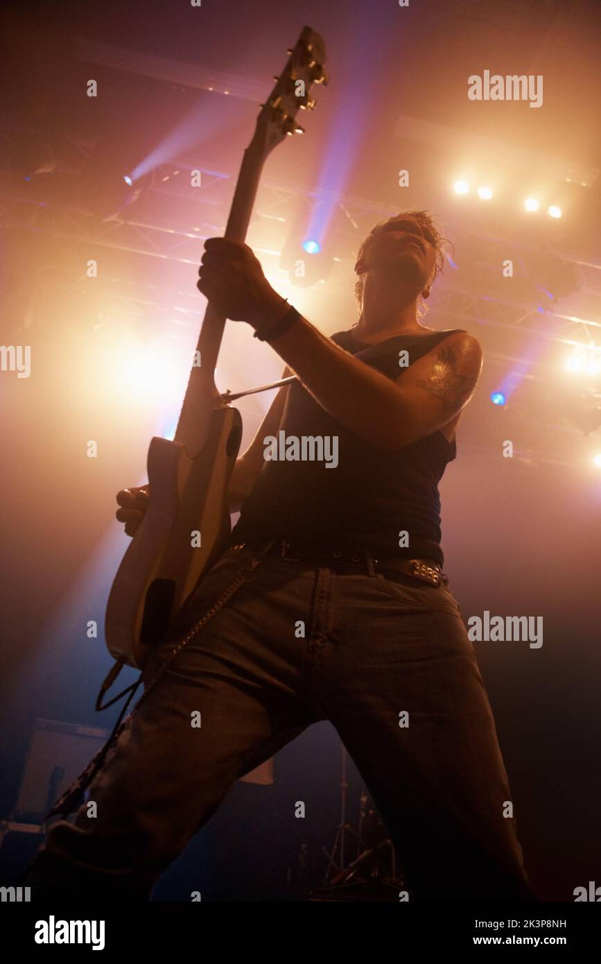 Delivering a rocking solo. Guitarist performing on stage at a music ...