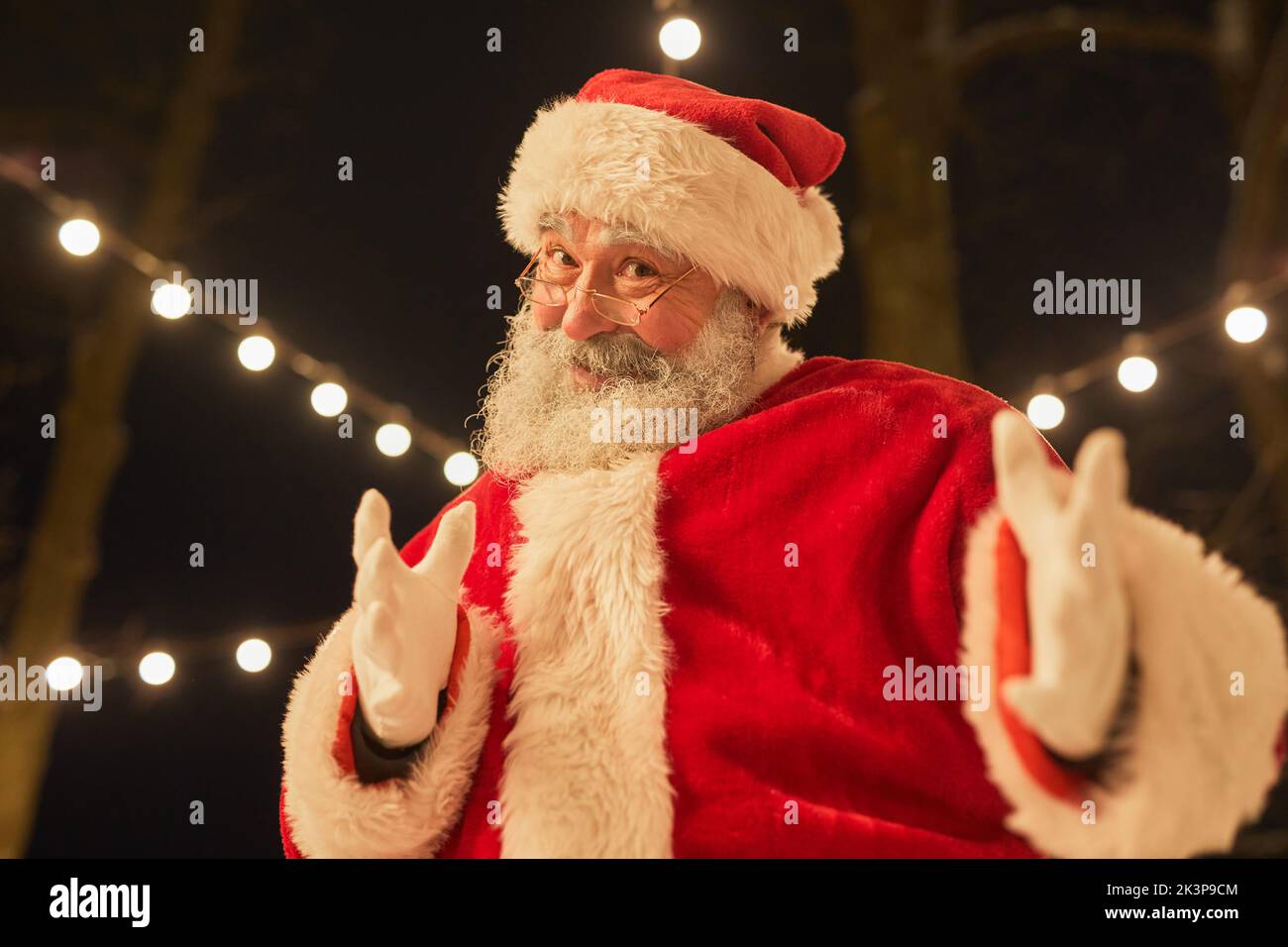 Waist up portrait of smiling Santa Claus inviting people while standing ...