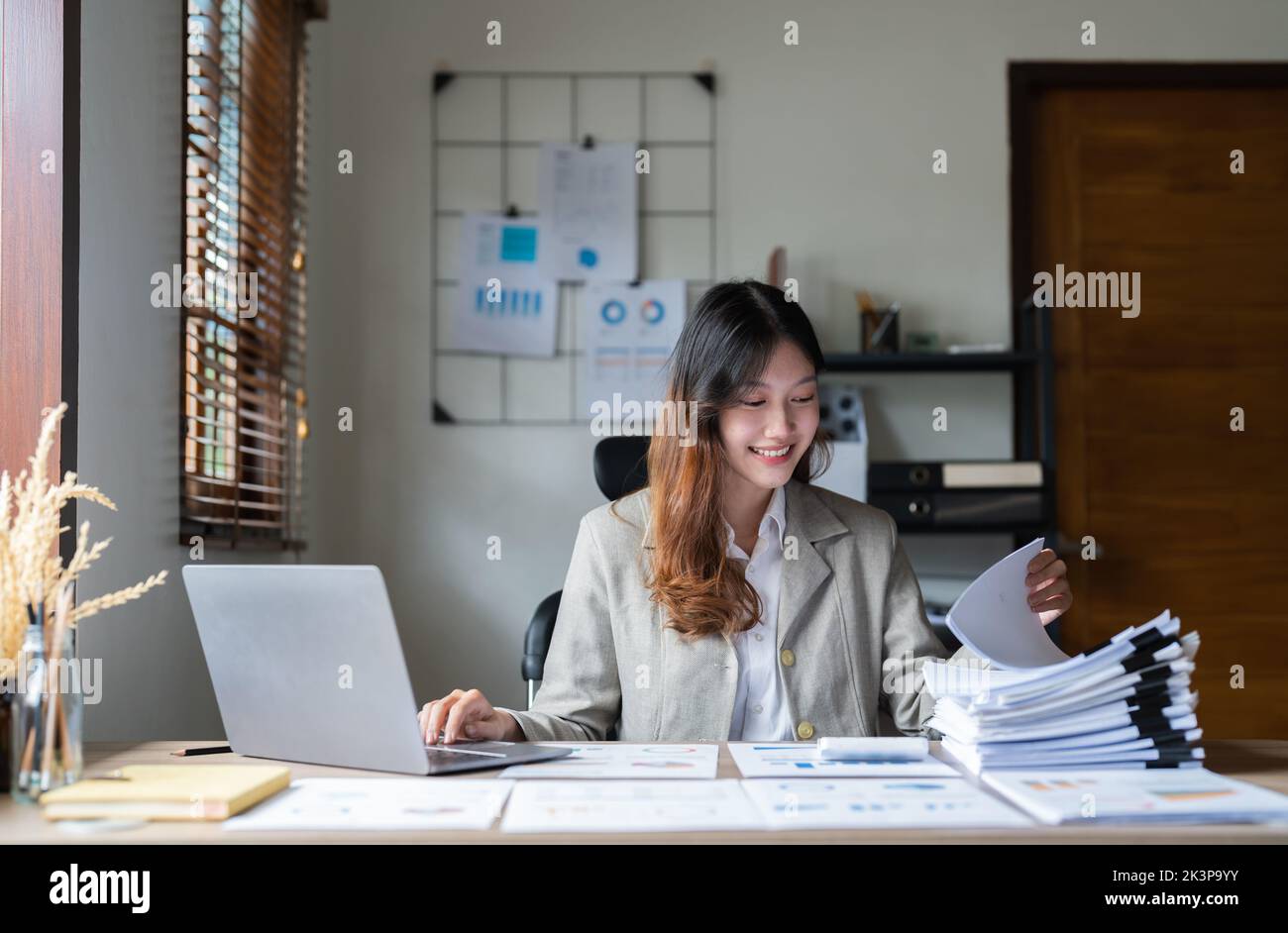 Young accountant working on laptop computer sitting at desk with pile ...