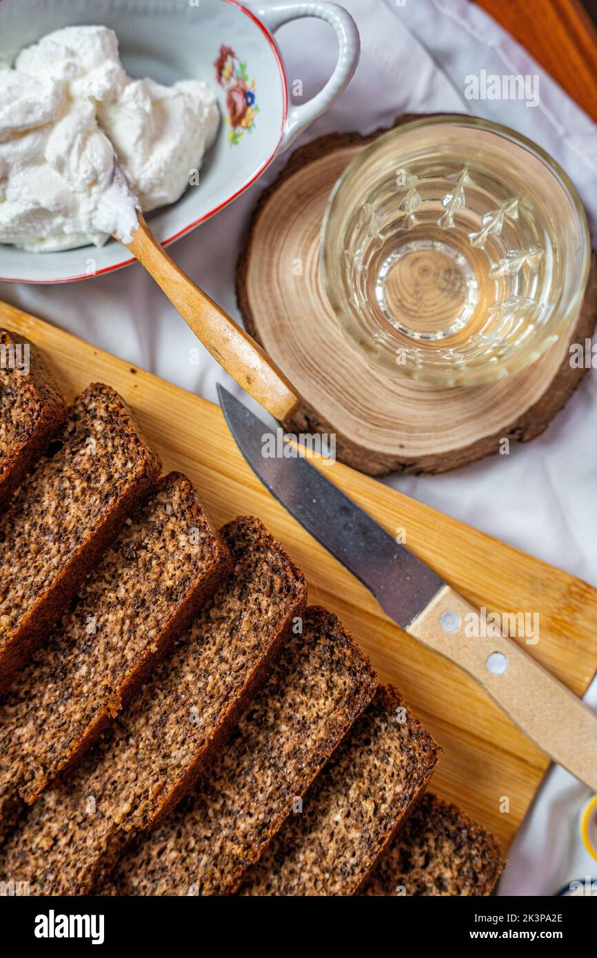 The vertical top view of sliced walnut bread, sour cream, and a glass ...