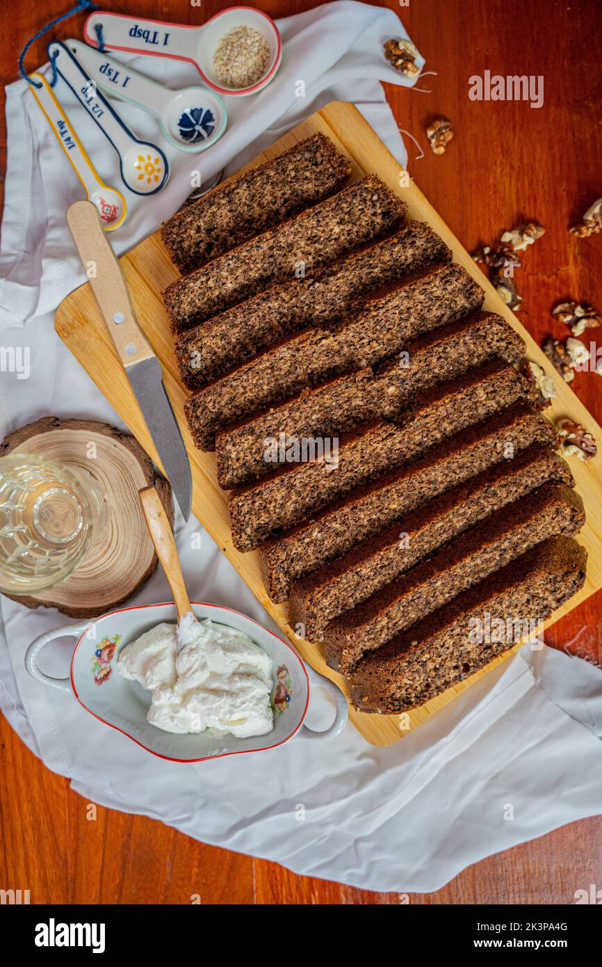 The vertical top view of sliced walnut bread, sour cream and spoons on ...