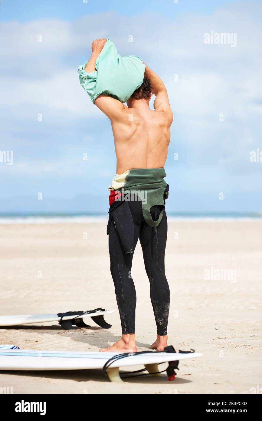 Getting ready to go surfing. A young man in a wetsuit getting ready for ...