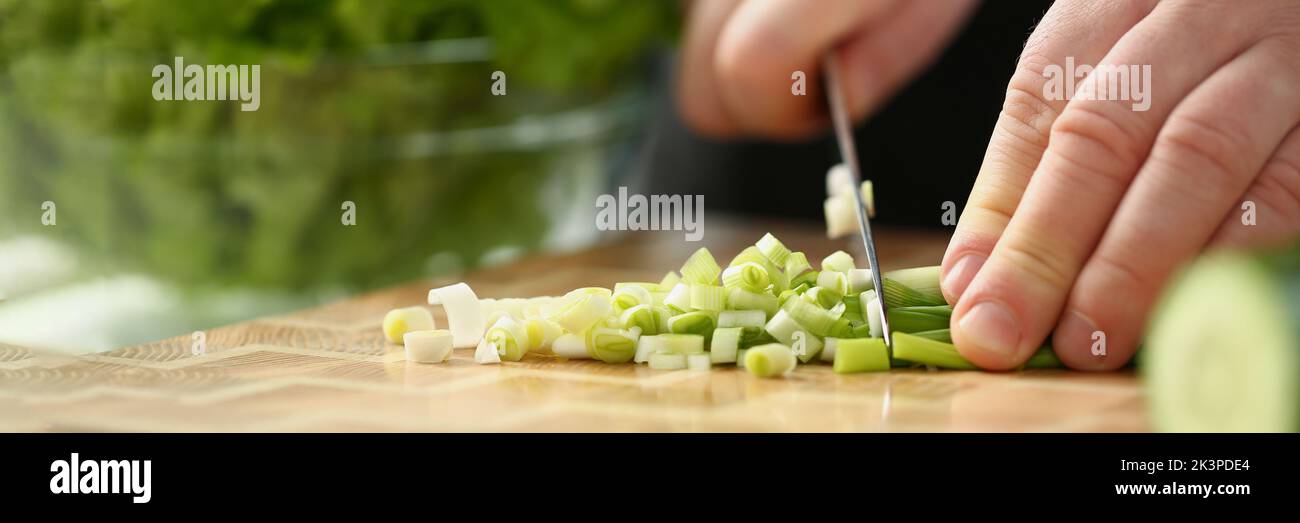 Professional chef cut spring onion with sharp knife on cutting board ...
