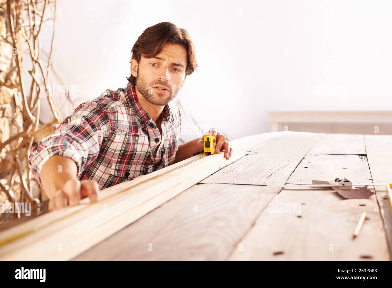 Hes a skilled carpenter. A handsome young carpenter measuring and ...