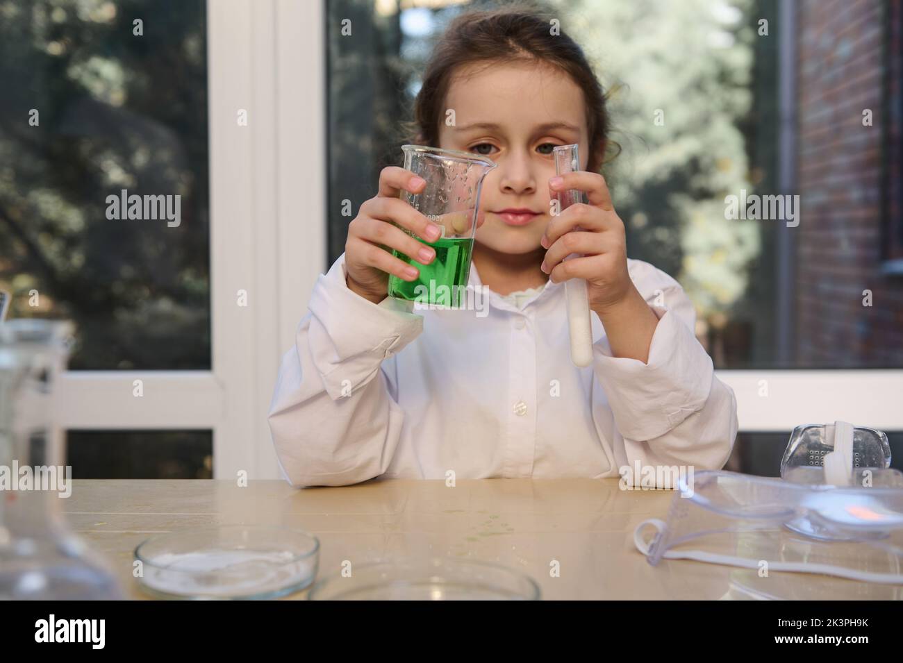 Hands of little chemist, carry out chemical reaction, pour solution of ...