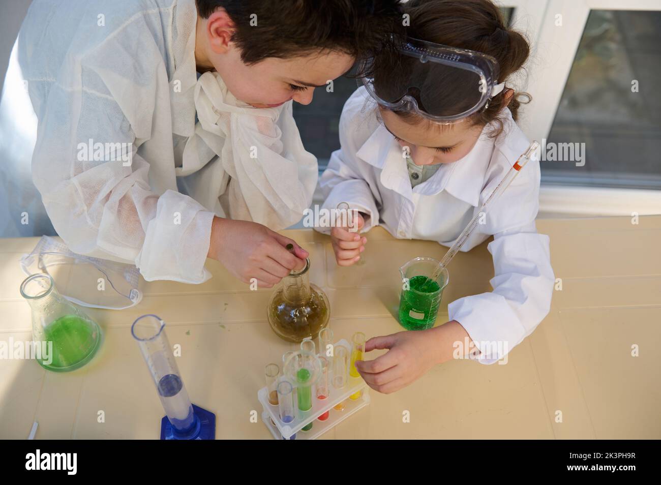 Top view of smart school kids conducting fascinating chemical ...