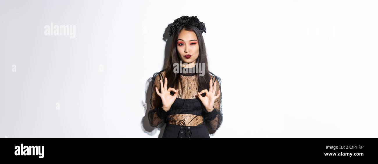 Image of stylish asian woman in gothic dress, looking satisfied and ...
