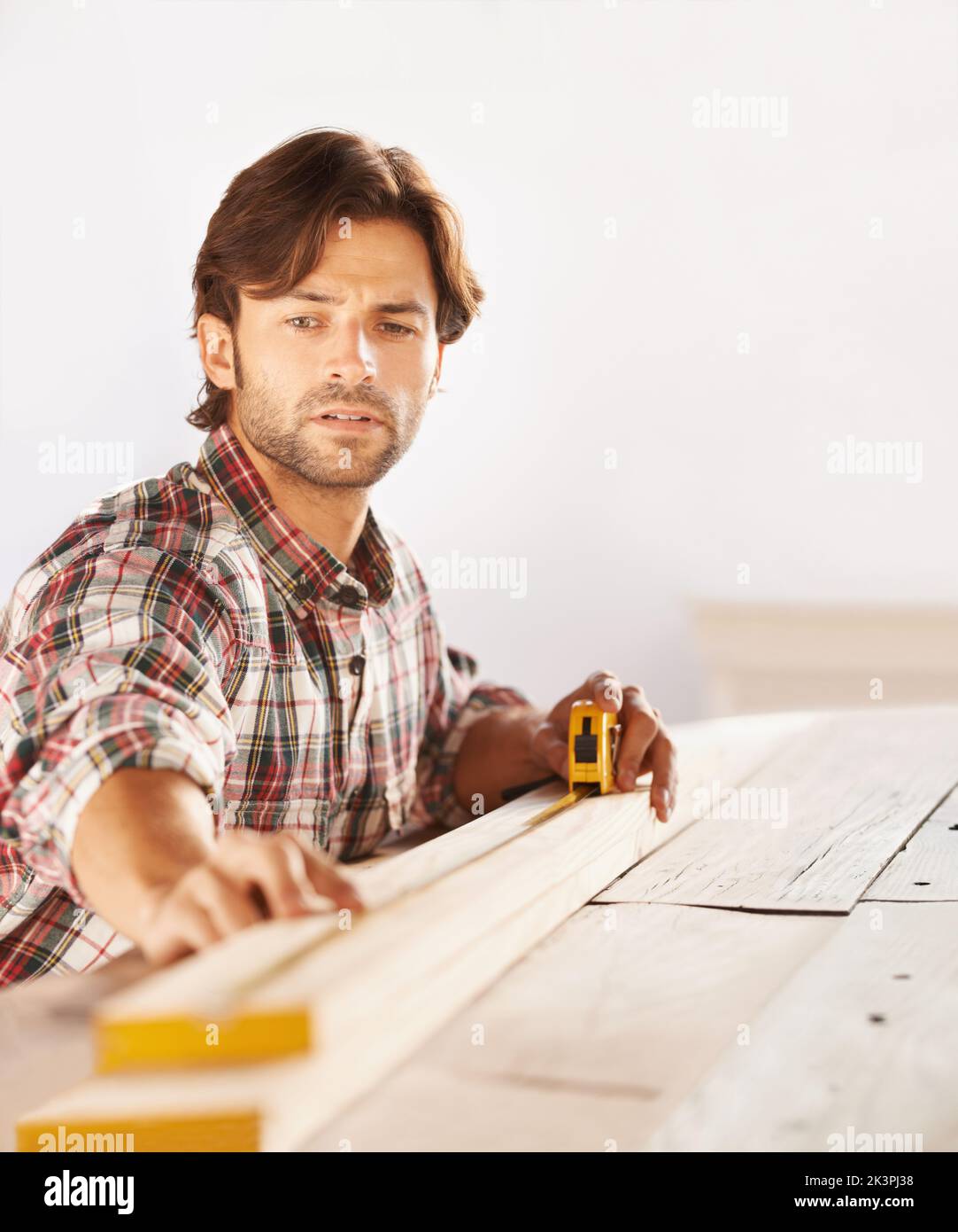 Getting it just right. A handsome young carpenter measuring and marking ...