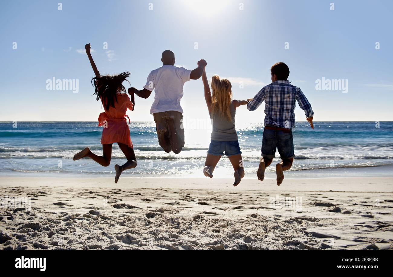 Celebrating summer time. Rear view of two young couple jumping together ...