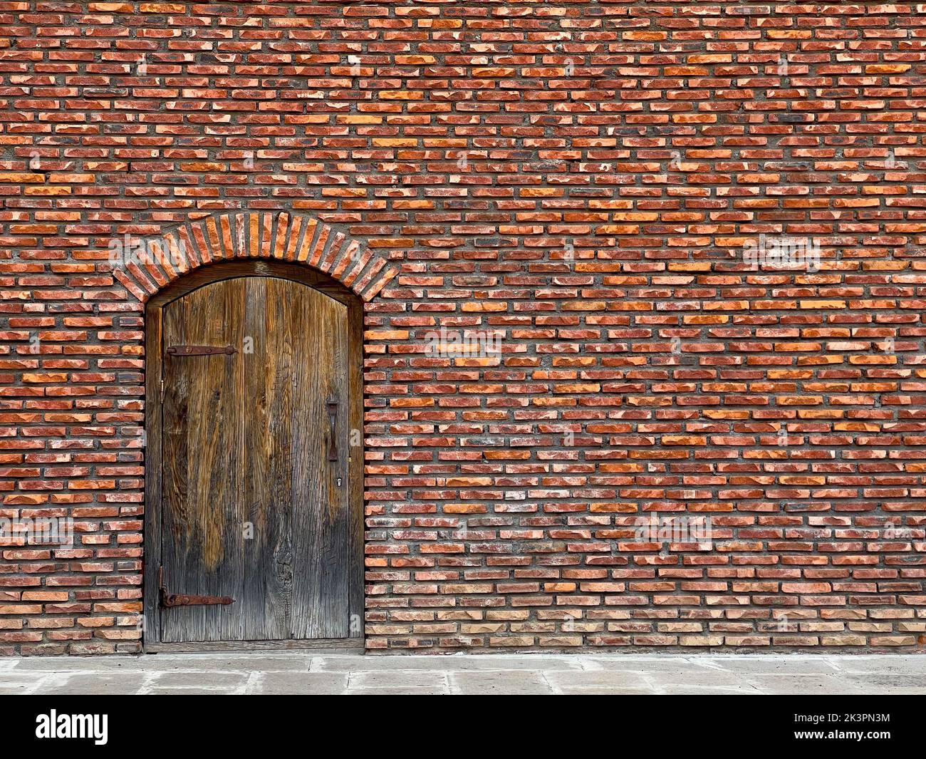 Red brick wall with arched wooden door Stock Photo - Alamy