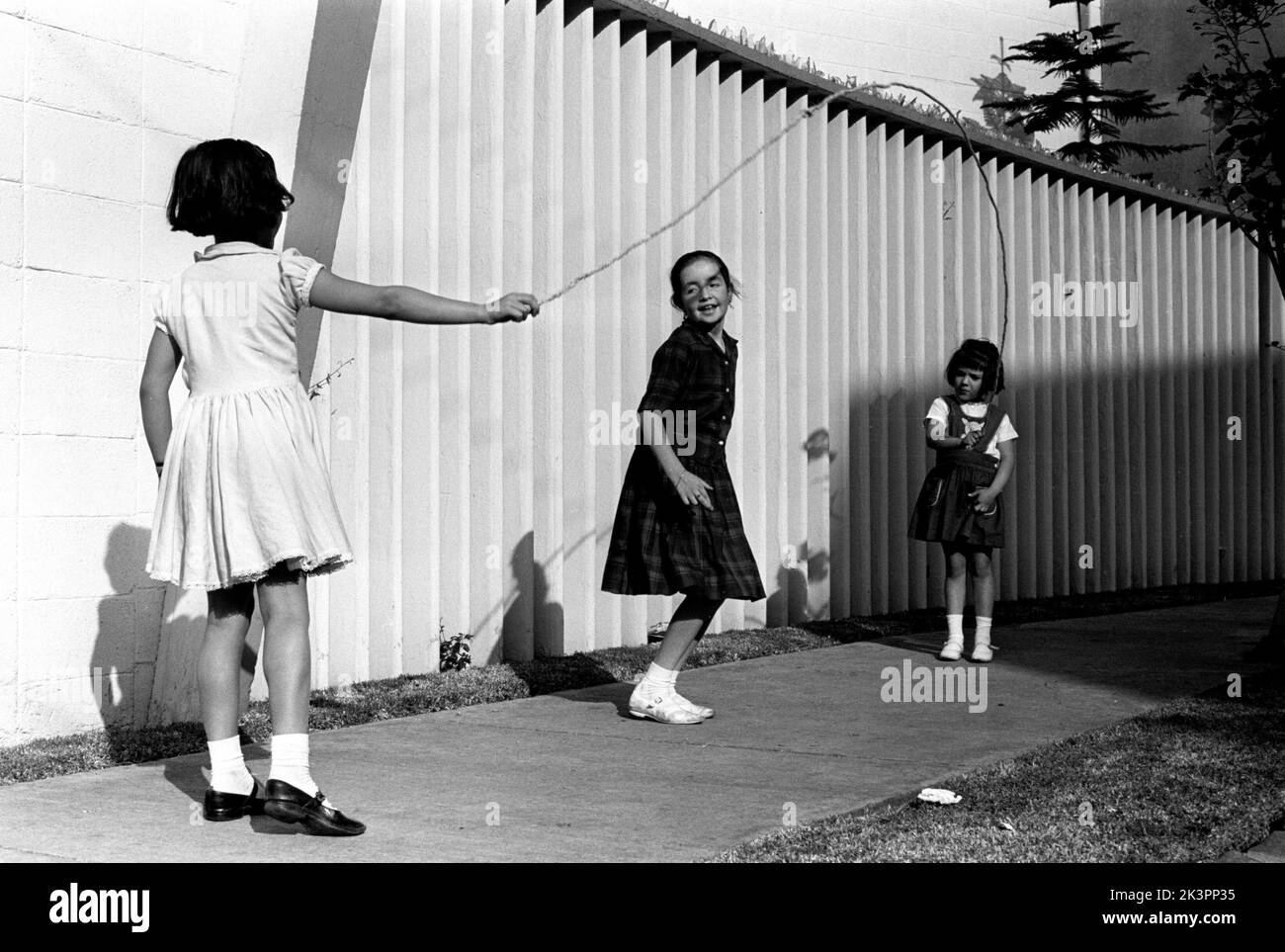 Mexico in the 1960s. Three girls are playing in the street, with a ...