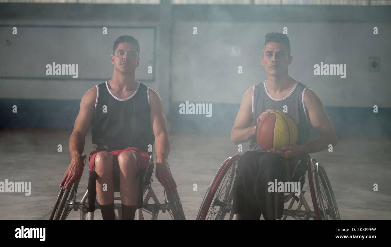Two disabled athletes in wheelchairs looking at camera holding ...
