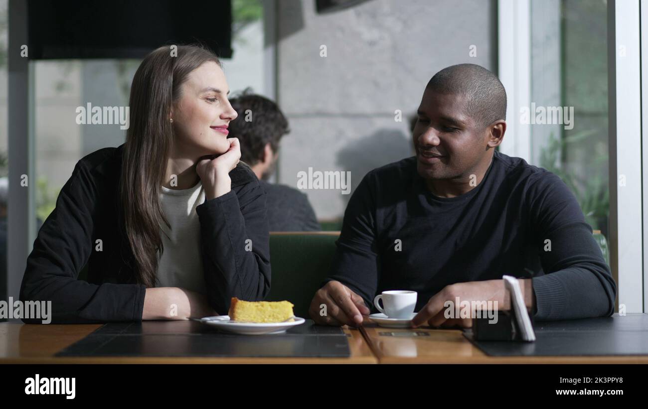 A diverse couple seated at coffee shop in conversation. Two People at ...