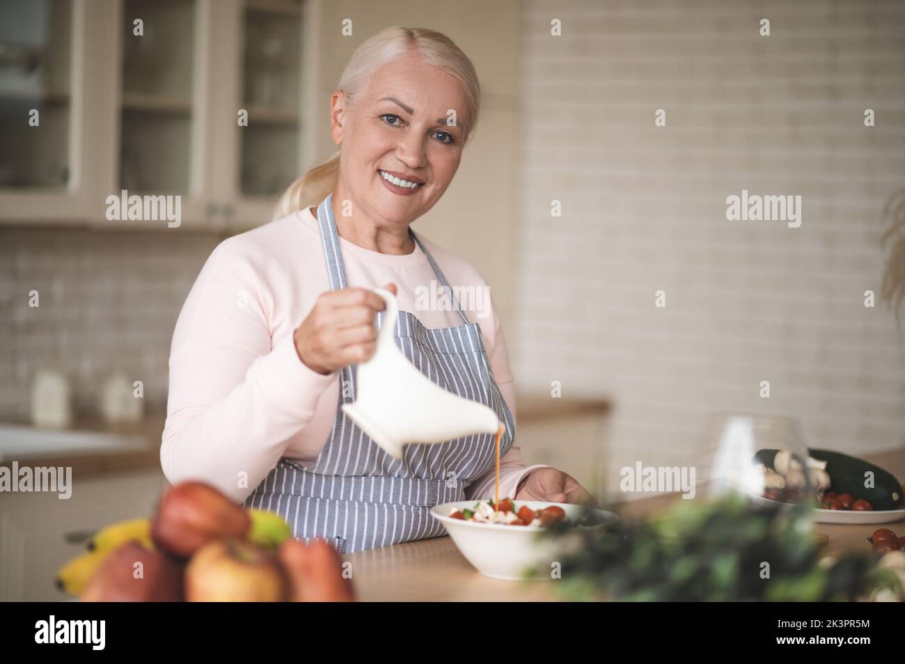 Female cook smiling at the camera while dressing the salad Stock Photo ...
