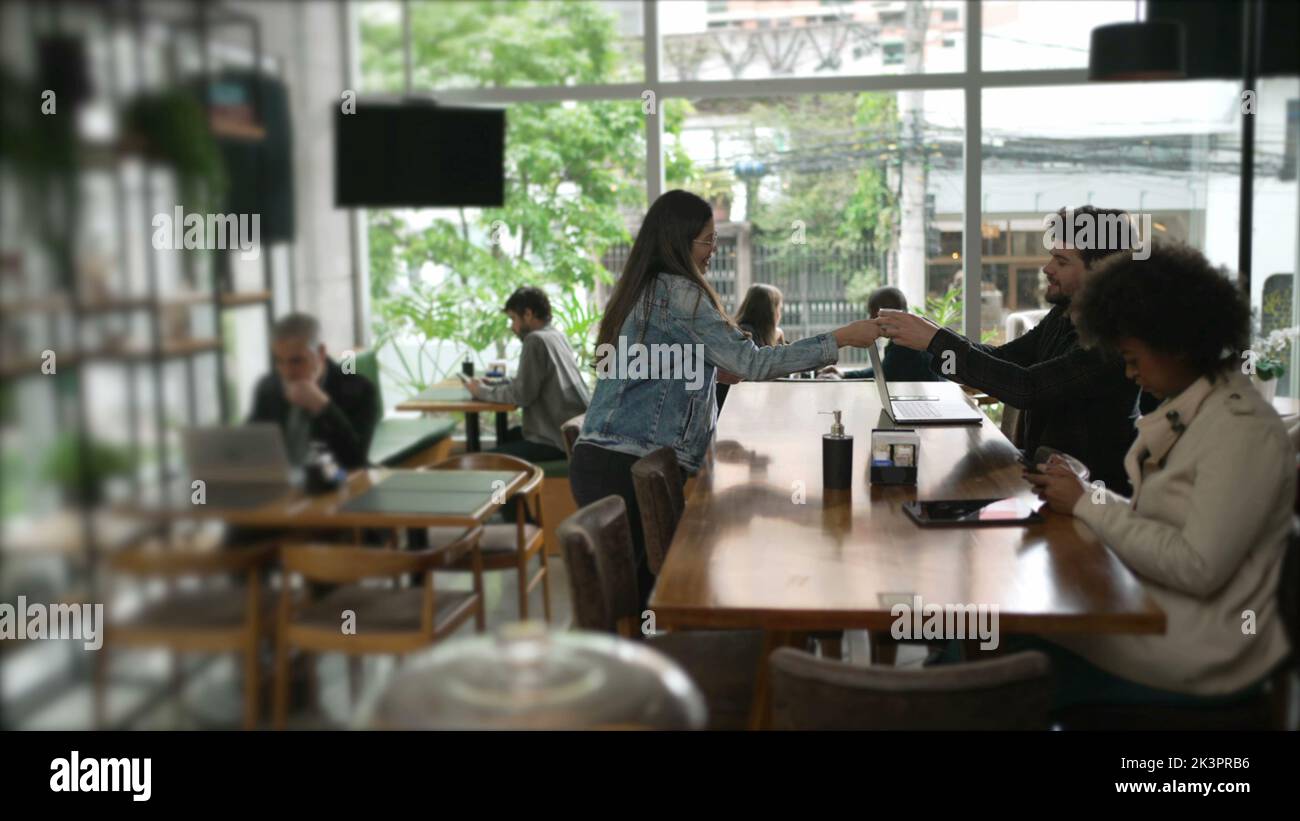 Customers inside coffee shop. Female friend bringing espresso to male ...