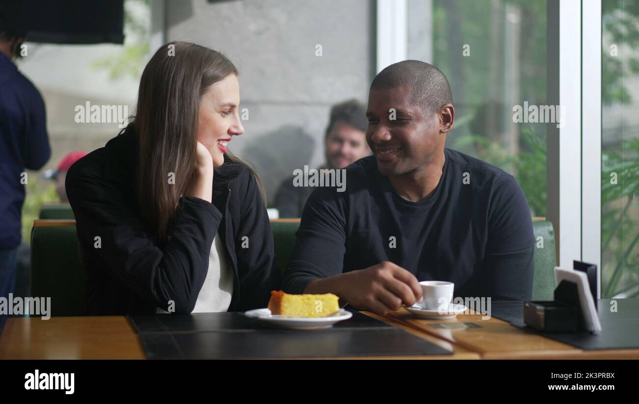 Diverse couple interaction seated at coffee shop. Two people in ...