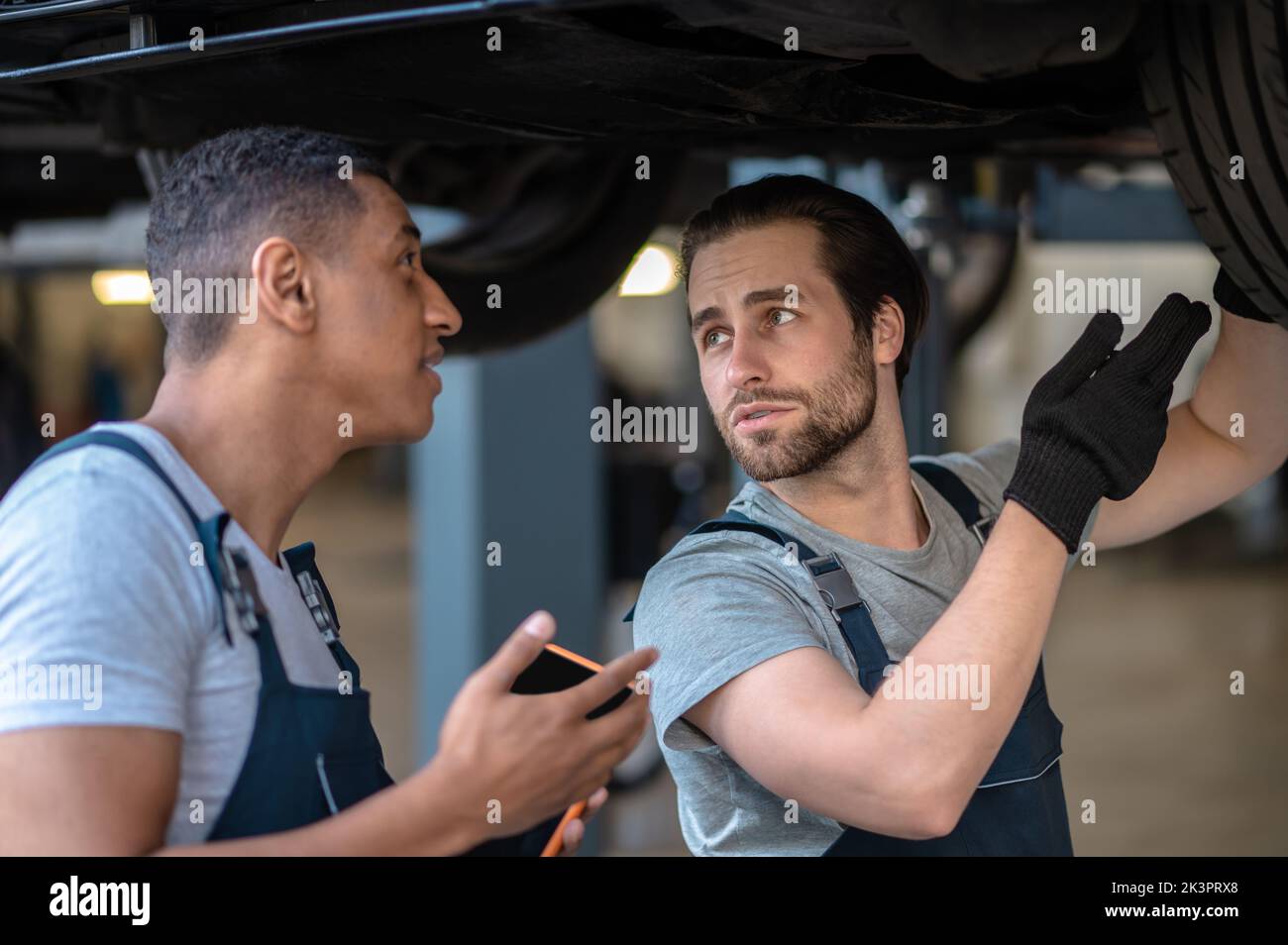 Two skilled mechanics checking the car tires Stock Photo - Alamy