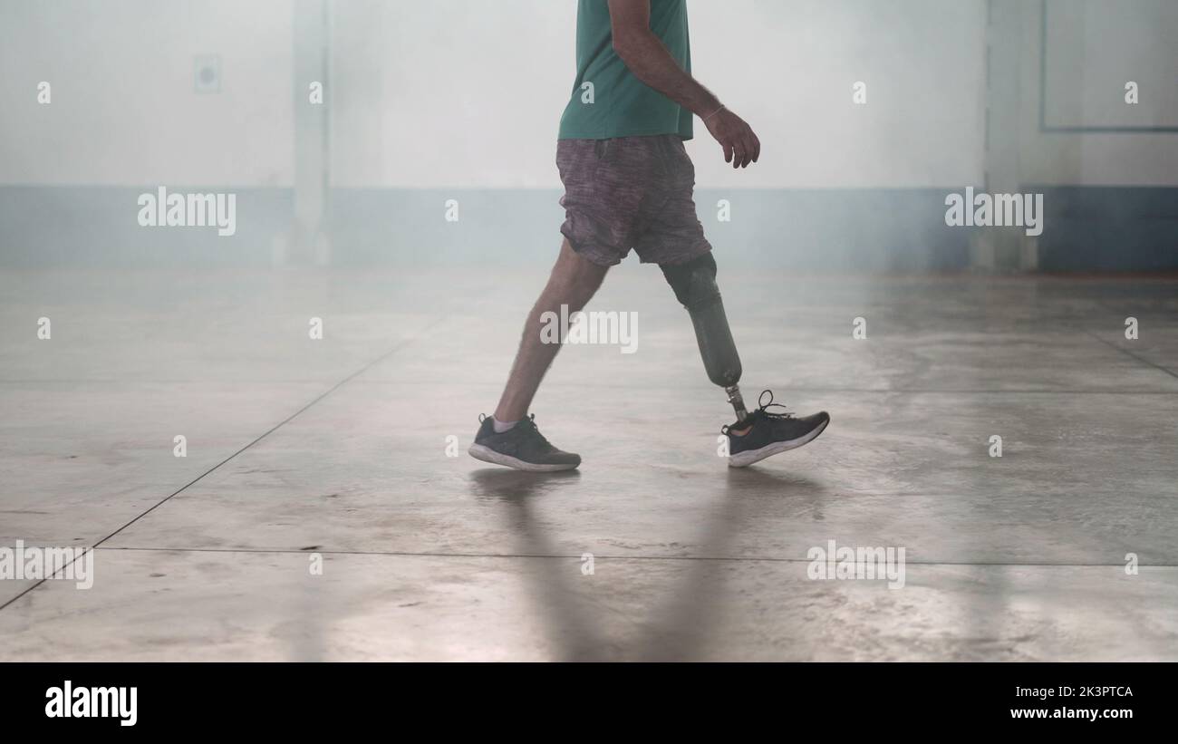 A disabled middle aged man walking with his prosthetic leg indoors ...