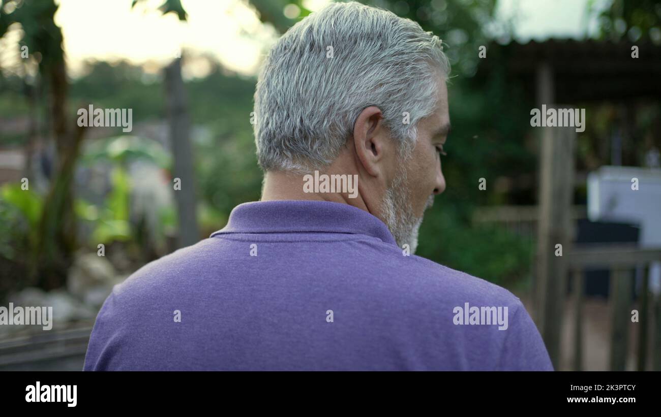 Back of contemplative senior man walking forward in nature. Pensive ...