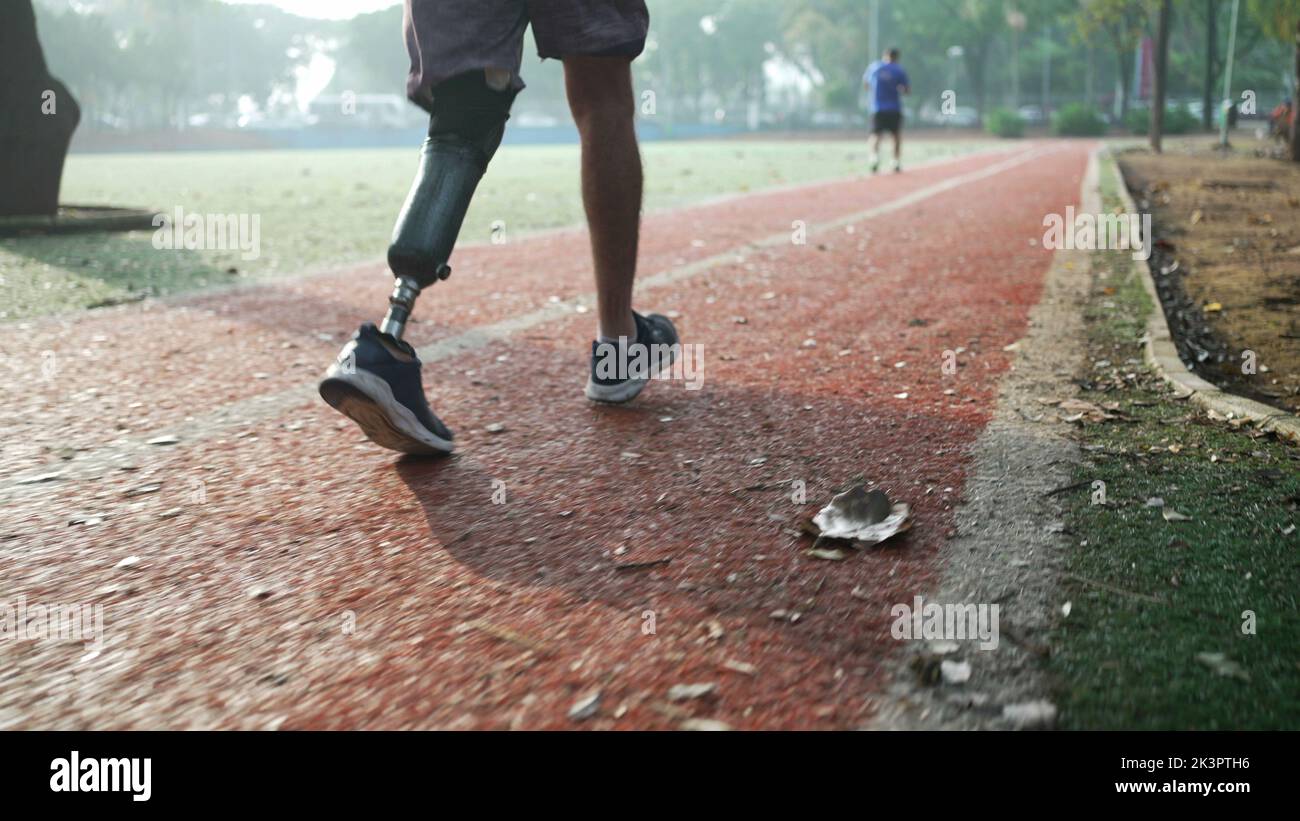 Determined disabled athlete running outside with prosthetic leg ...