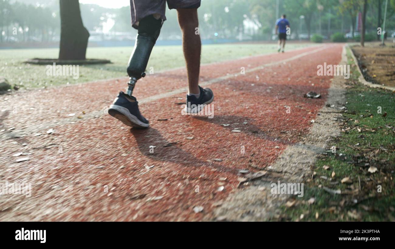 Determined disabled athlete running outside with prosthetic leg ...