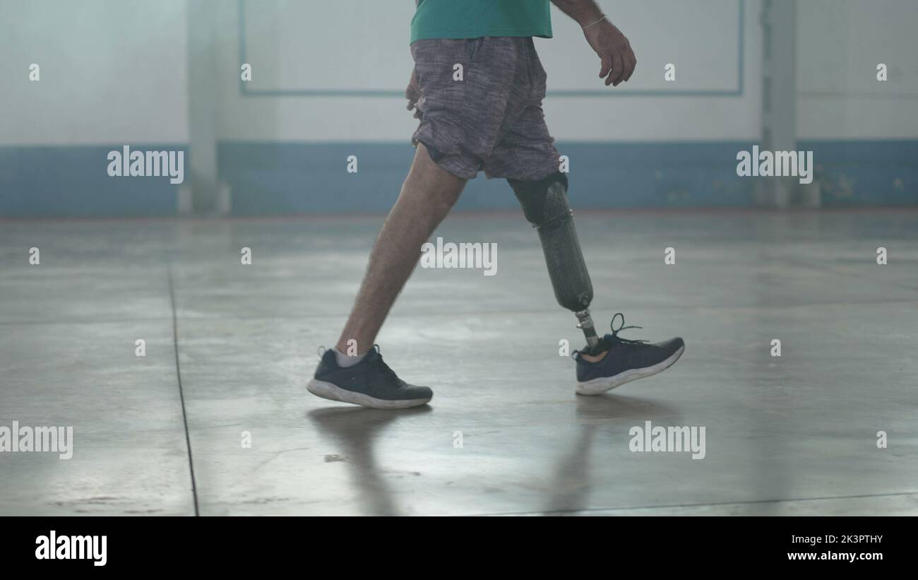 Disabled person walking with his prosthetic leg indoors. Amputee man ...