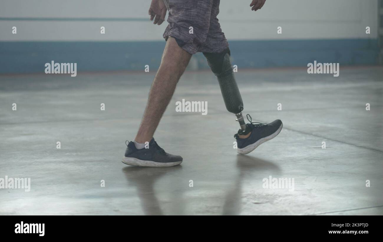 Disabled person walking with his prosthetic leg indoors. Amputee man ...