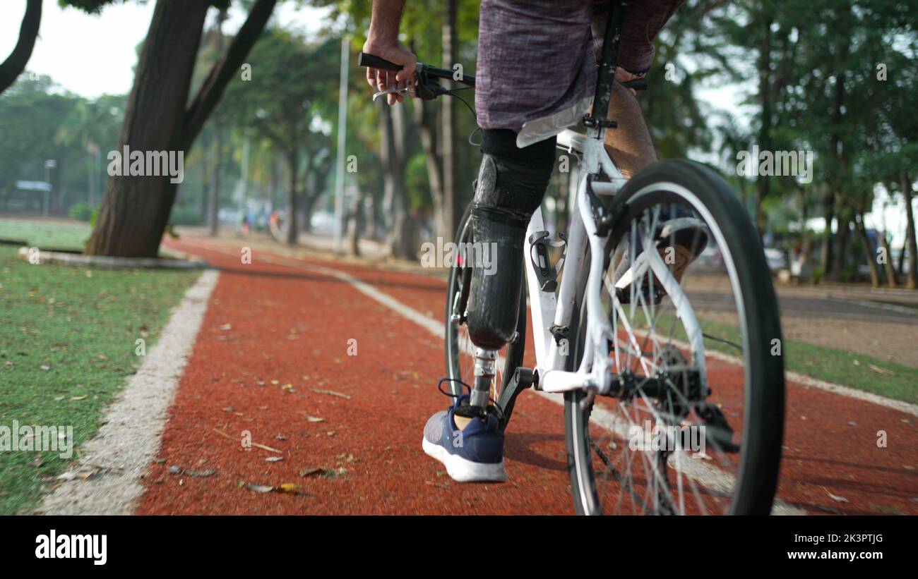 Disabled person riding bicycle using prosthetic leg outdoors Stock ...