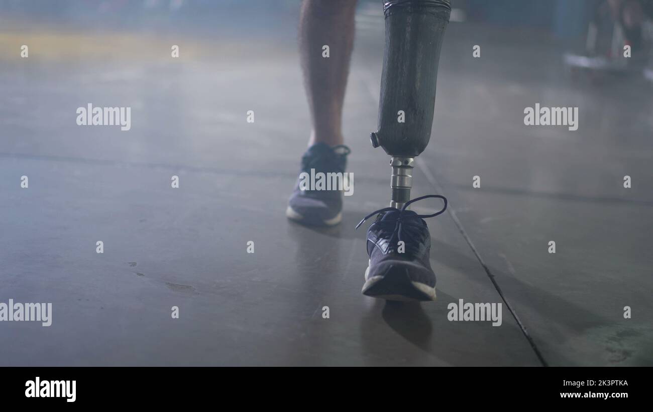 Disabled person walking with his prosthetic leg indoors. Amputee man ...