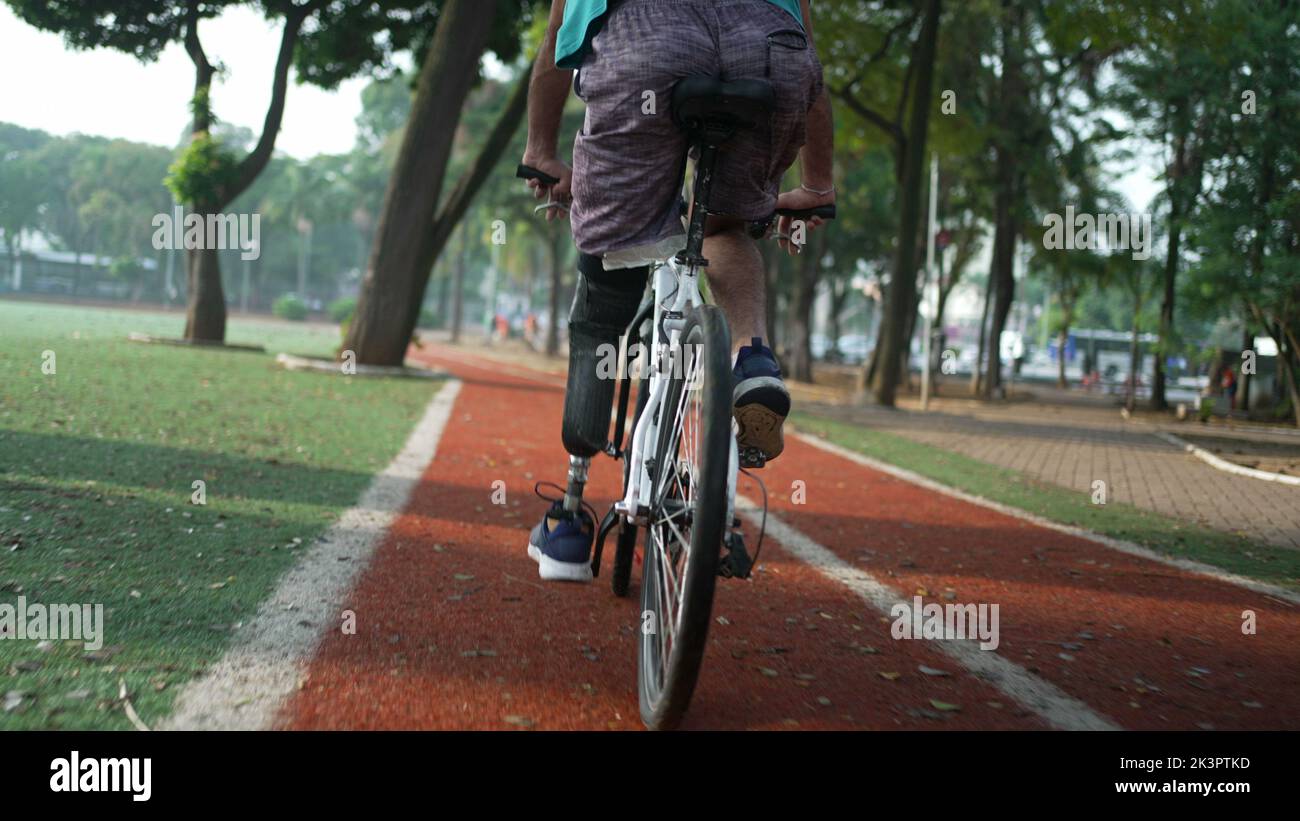 Disabled person riding bicycle using prosthetic leg outdoors Stock ...