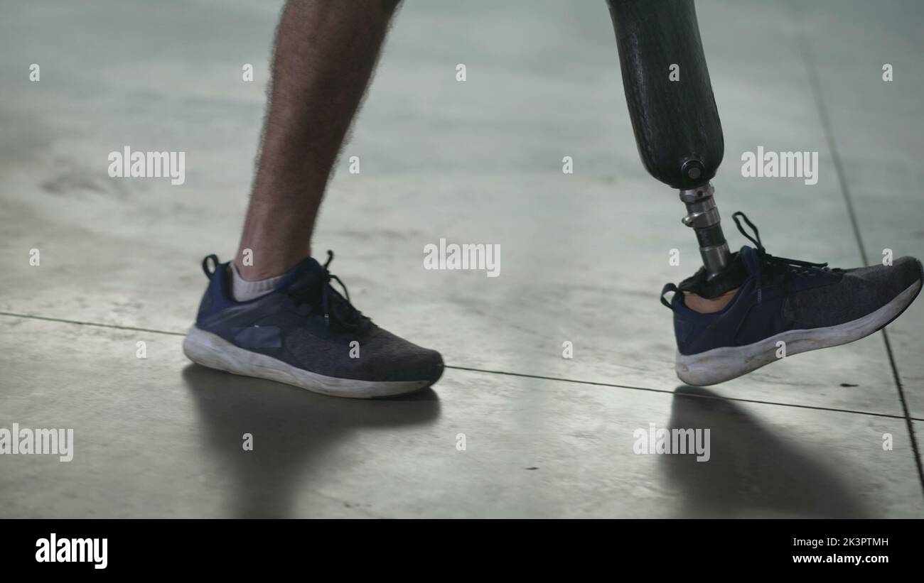 Disabled person walking with his prosthetic leg indoors. Amputee man ...