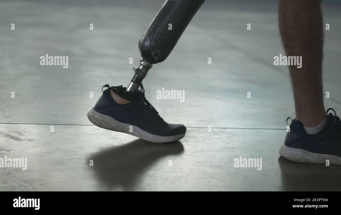 Disabled person walking with his prosthetic leg indoors. Amputee man ...