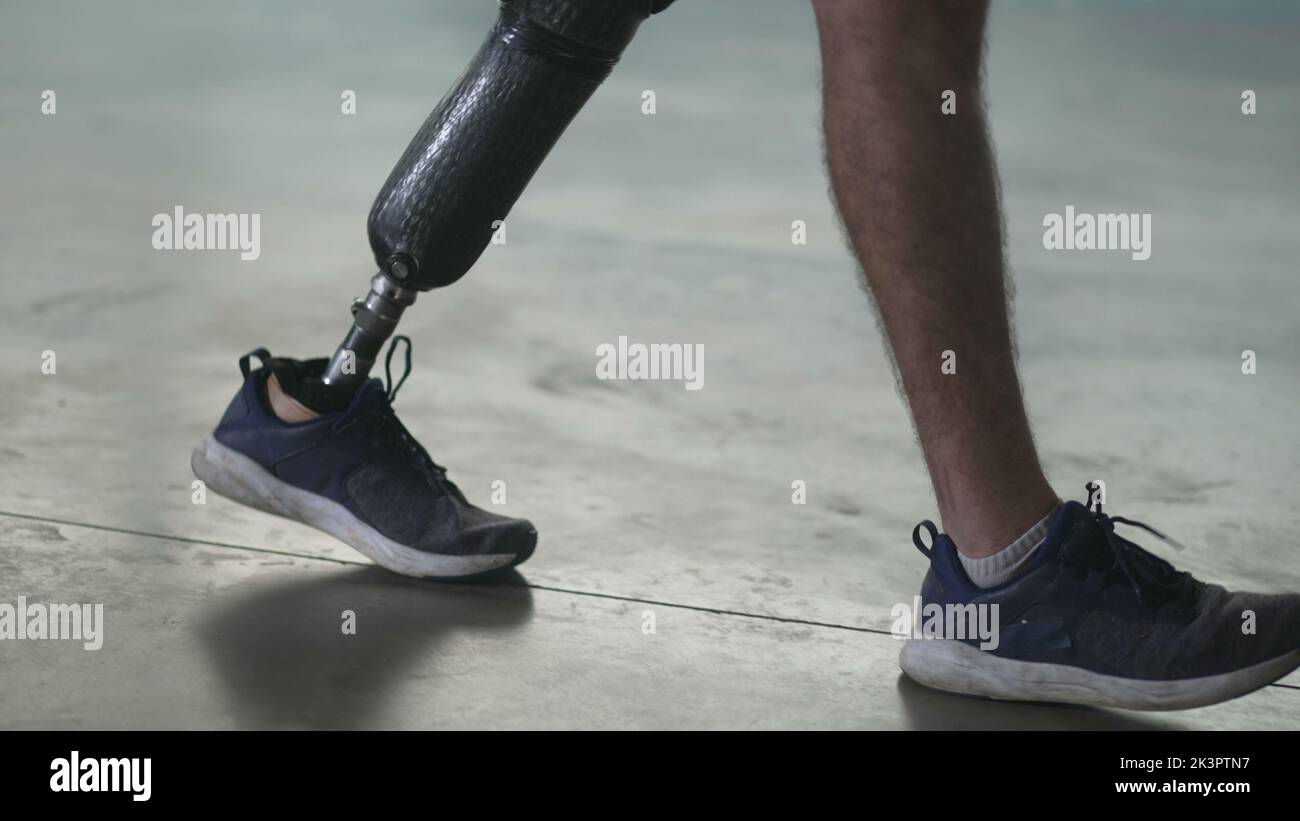 Disabled person walking with his prosthetic leg indoors. Amputee man ...