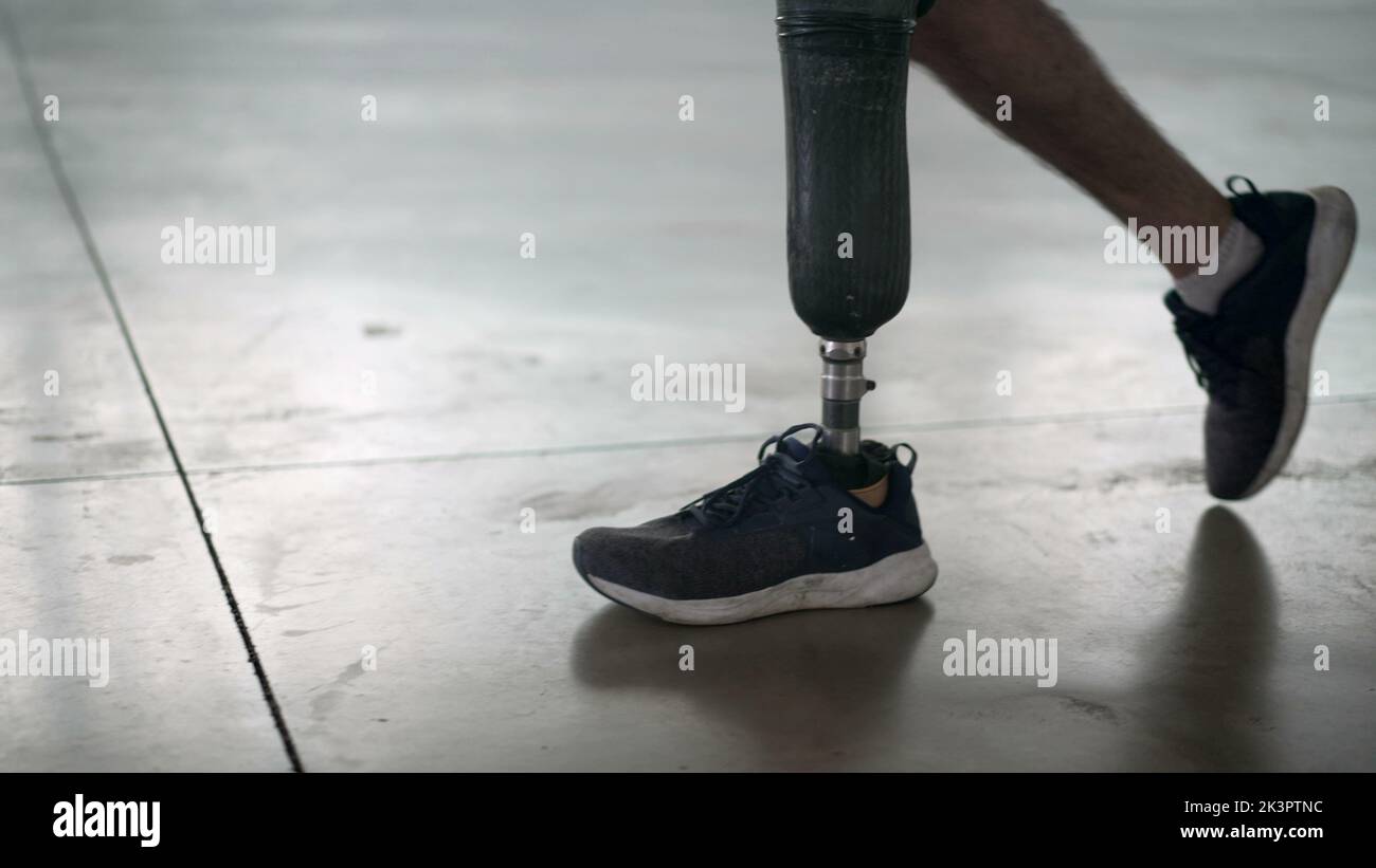 Disabled person walking with his prosthetic leg indoors. Amputee man ...
