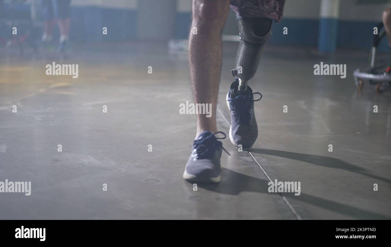Disabled person walking with his prosthetic leg indoors. Amputee man ...