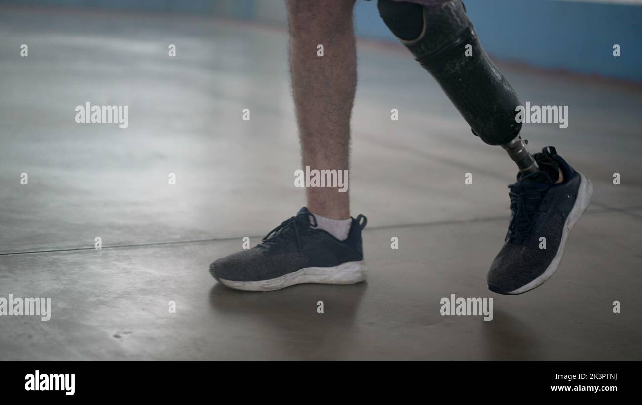 Disabled person walking with his prosthetic leg indoors. Amputee man ...