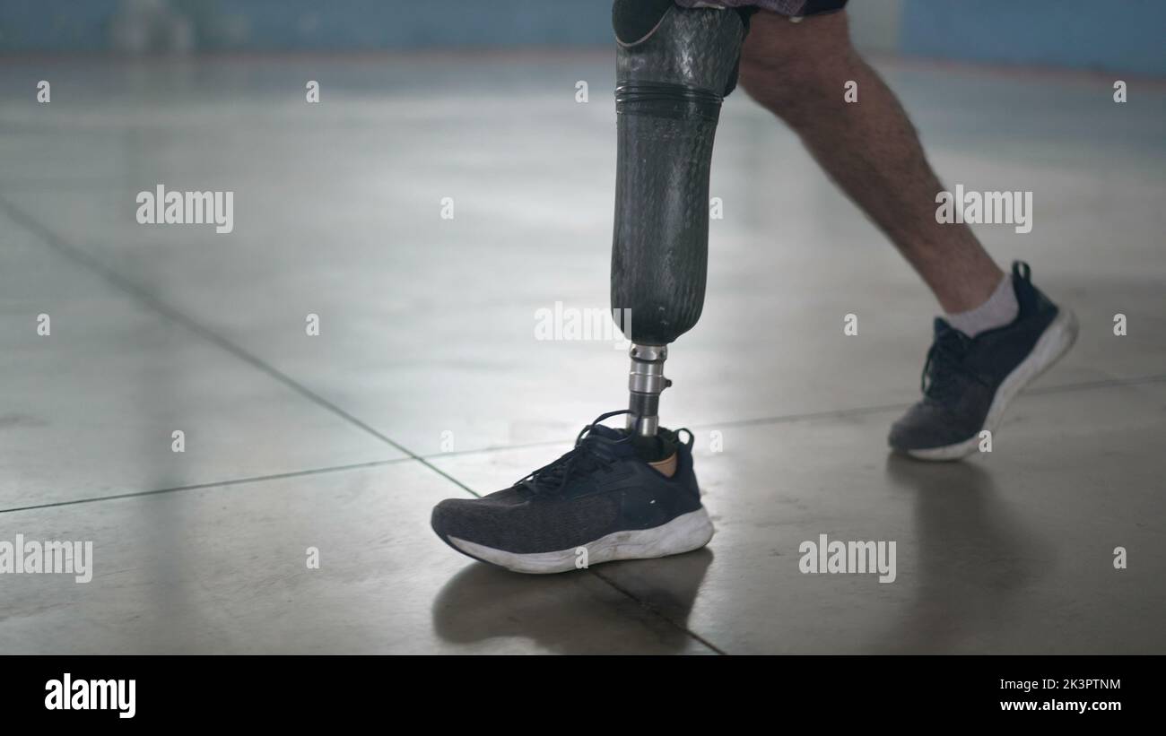 Disabled person walking with his prosthetic leg indoors. Amputee man ...