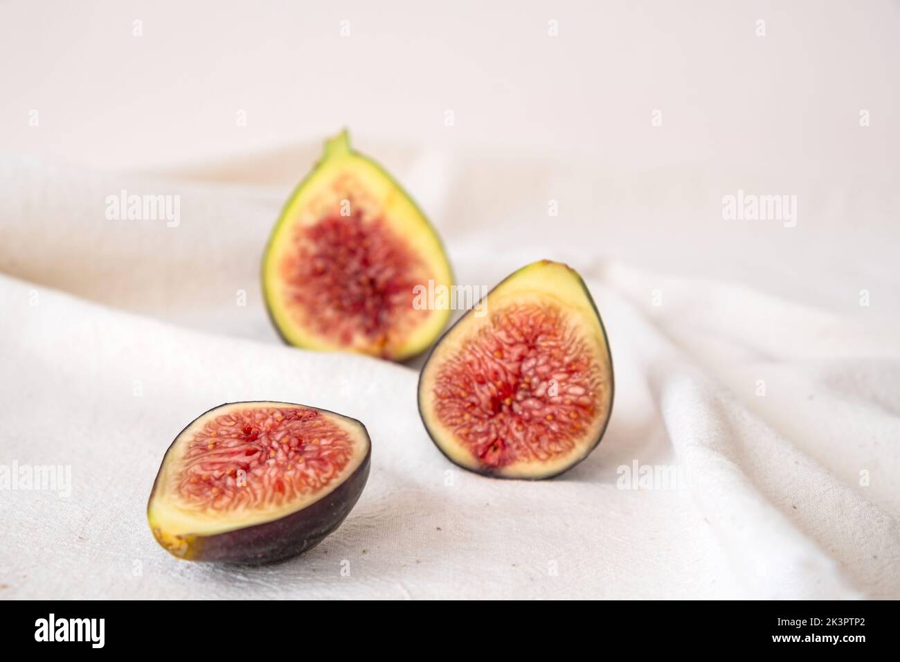 Fresh ripe and sweet figs cut and whole on beige color table cloth ...