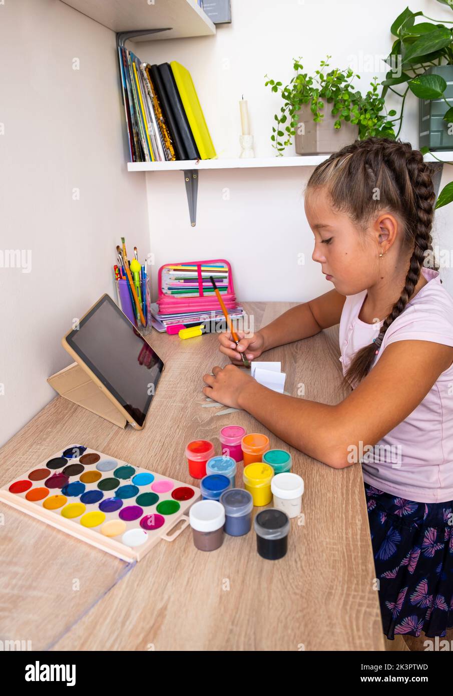 A happy girl is happy painting with paints. Distance education concept ...