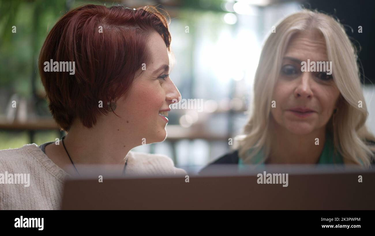 Two people in different ages looking at computer screen. Happy female ...