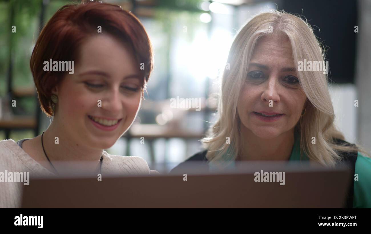 Two people in different ages looking at computer screen. Happy female ...