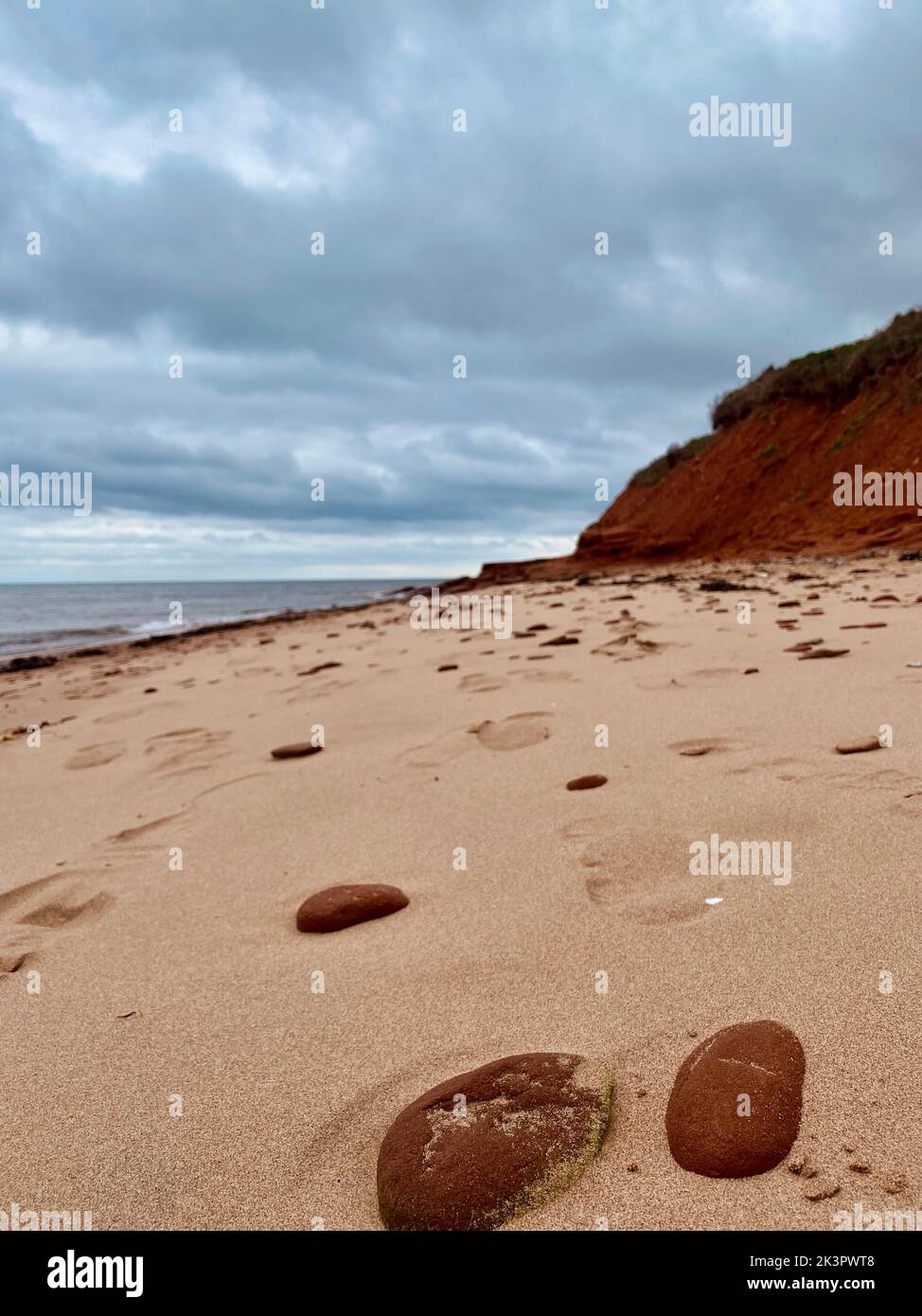 The red sandstone cliffs and the sand at Cavendish Beach under cloudy ...