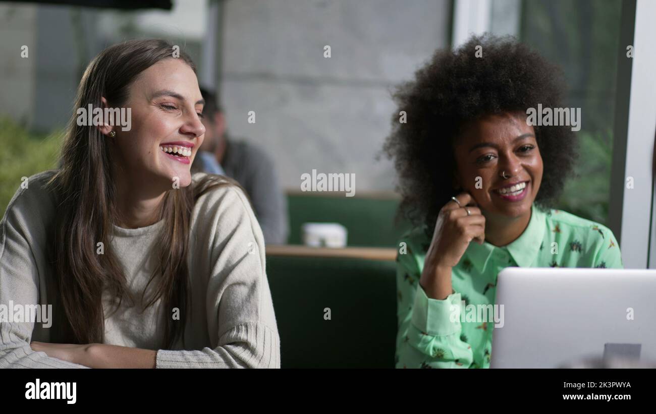 Young diverse group of friends laughing and smiling seated at coffee ...