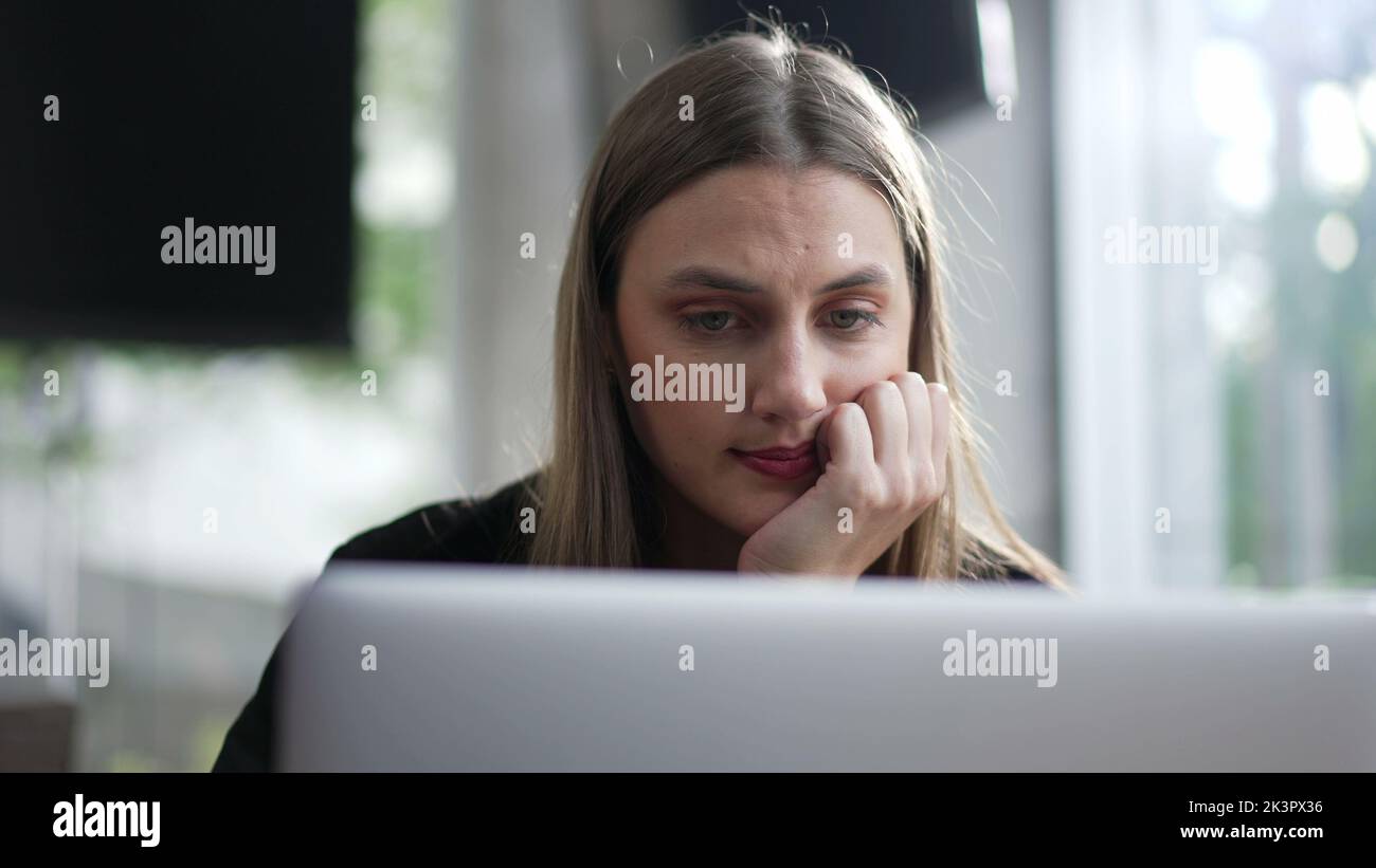 Young woman face looking at laptop computer seated at coffee shop ...