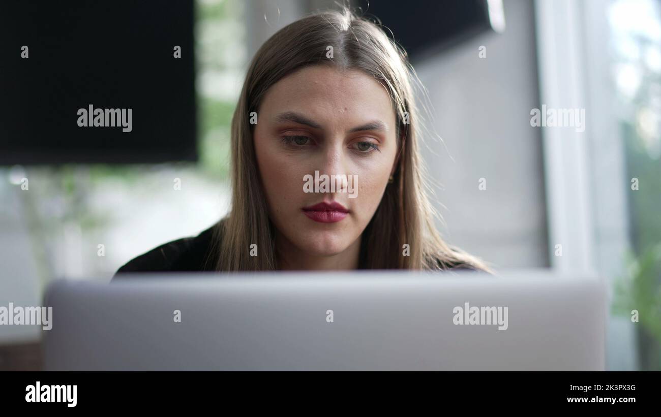 Young woman face looking at laptop computer seated at coffee shop ...